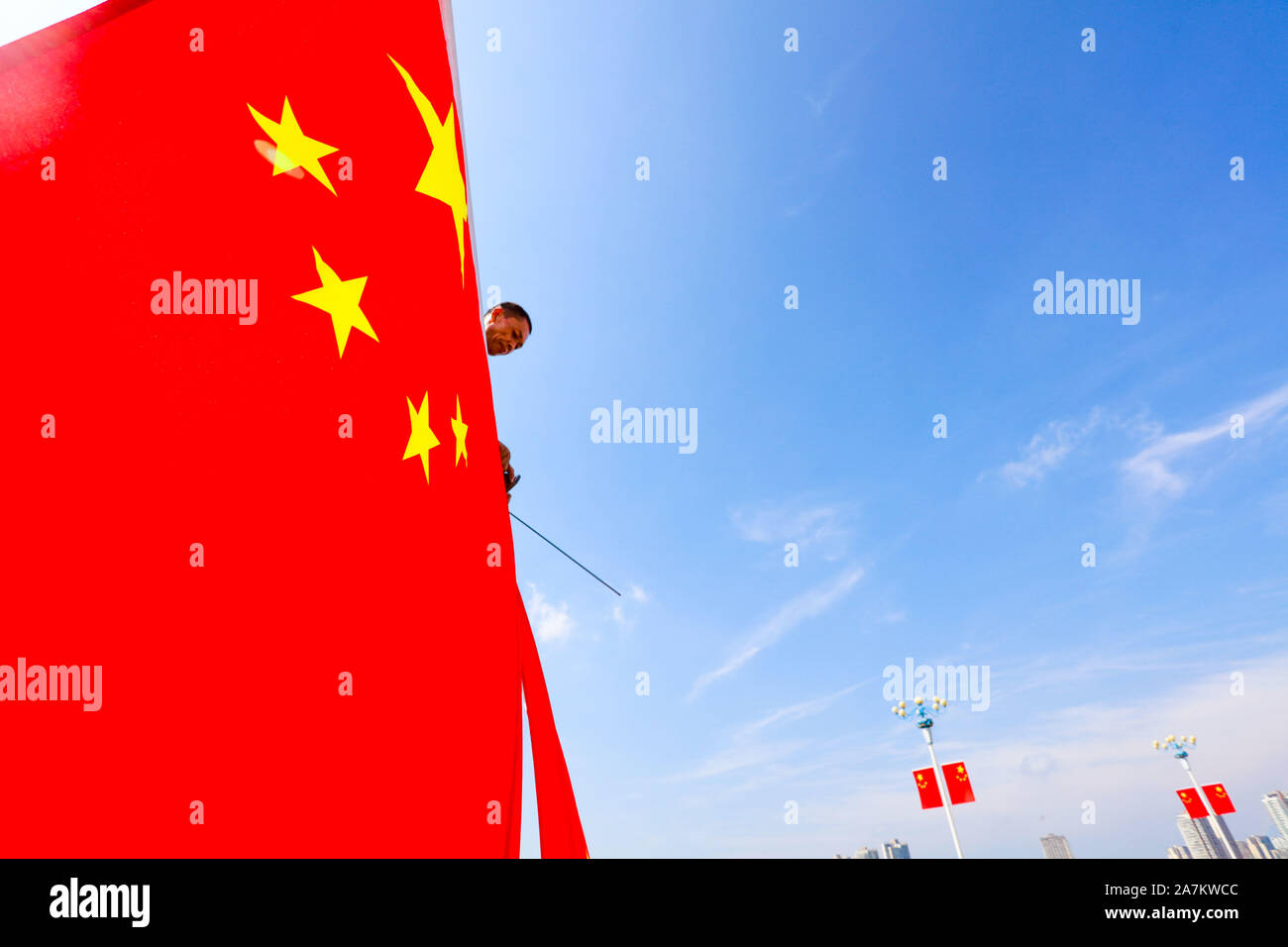 Workers hang national flags in streets to celebrate the 70th National ...