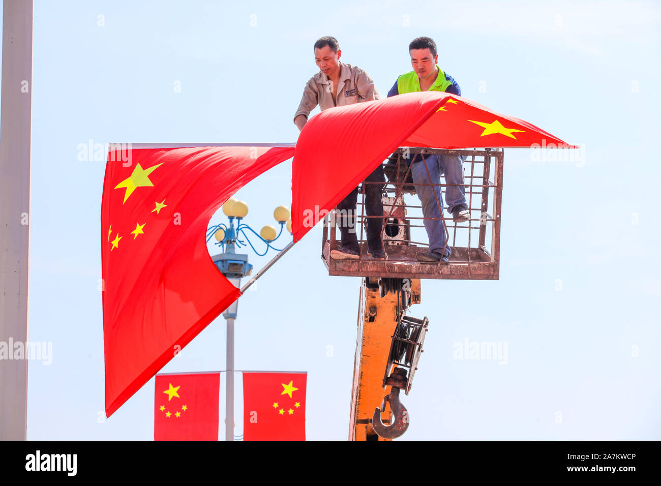 Workers hang national flags in streets to celebrate the 70th National ...
