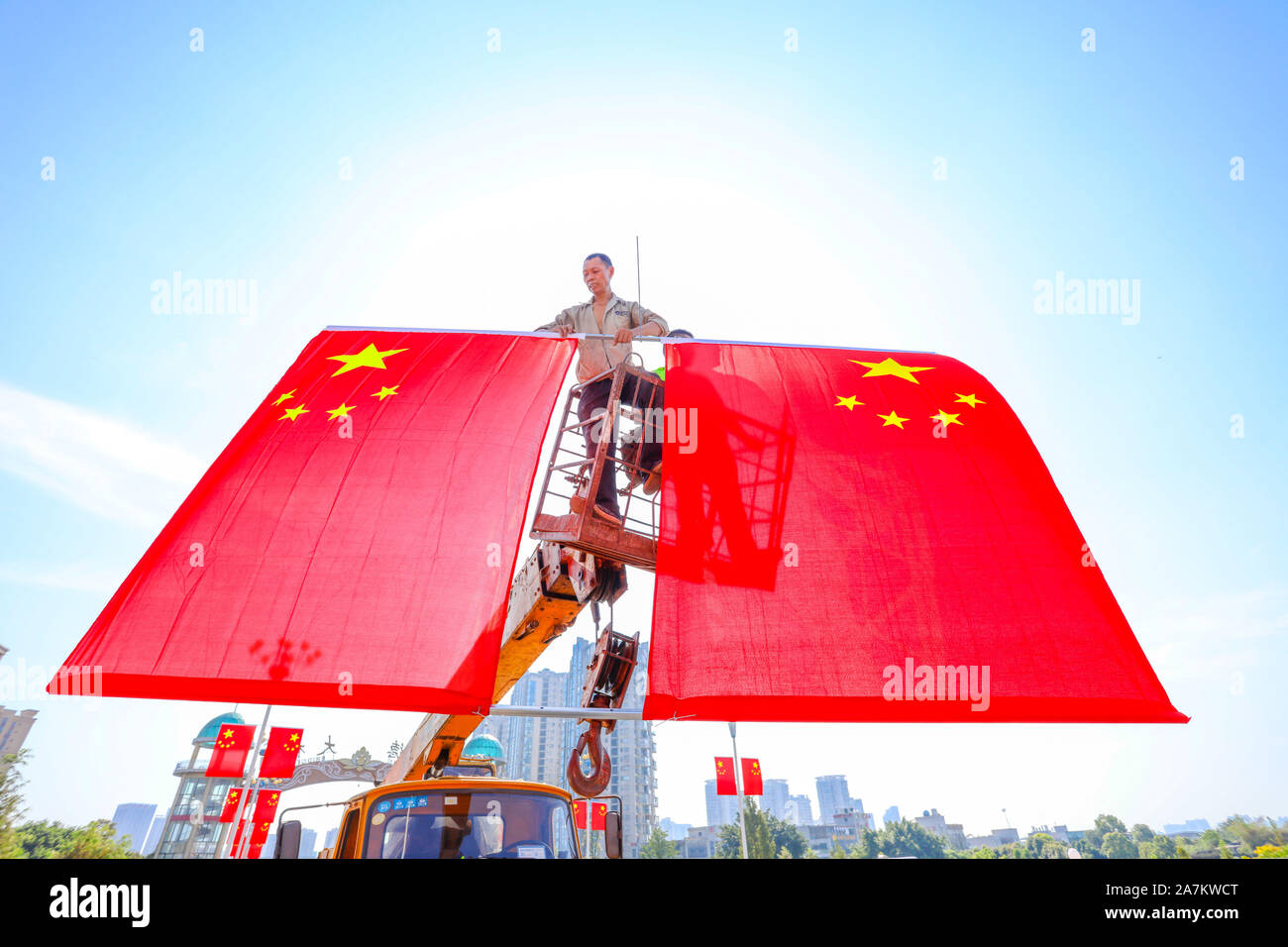 Workers hang national flags in streets to celebrate the 70th National ...