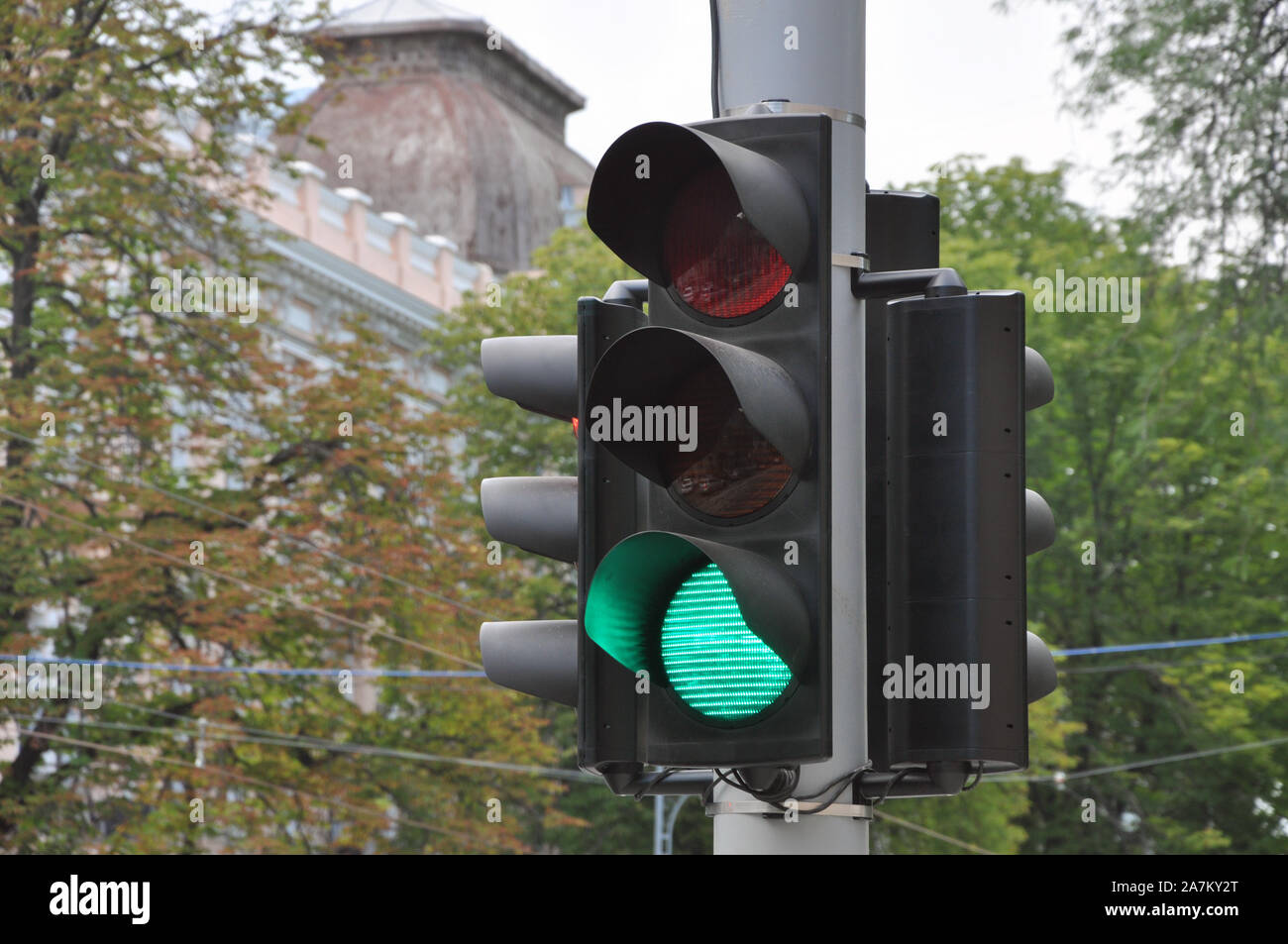 Green color of a traffic light against the background of a modern city ...