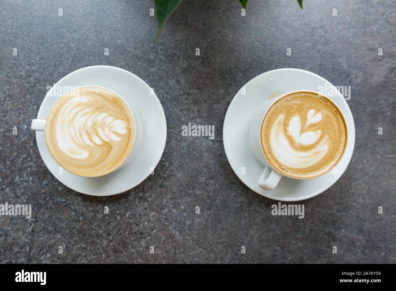 Two white cups of coffee art on gray stone countertop Stock Photo - Alamy