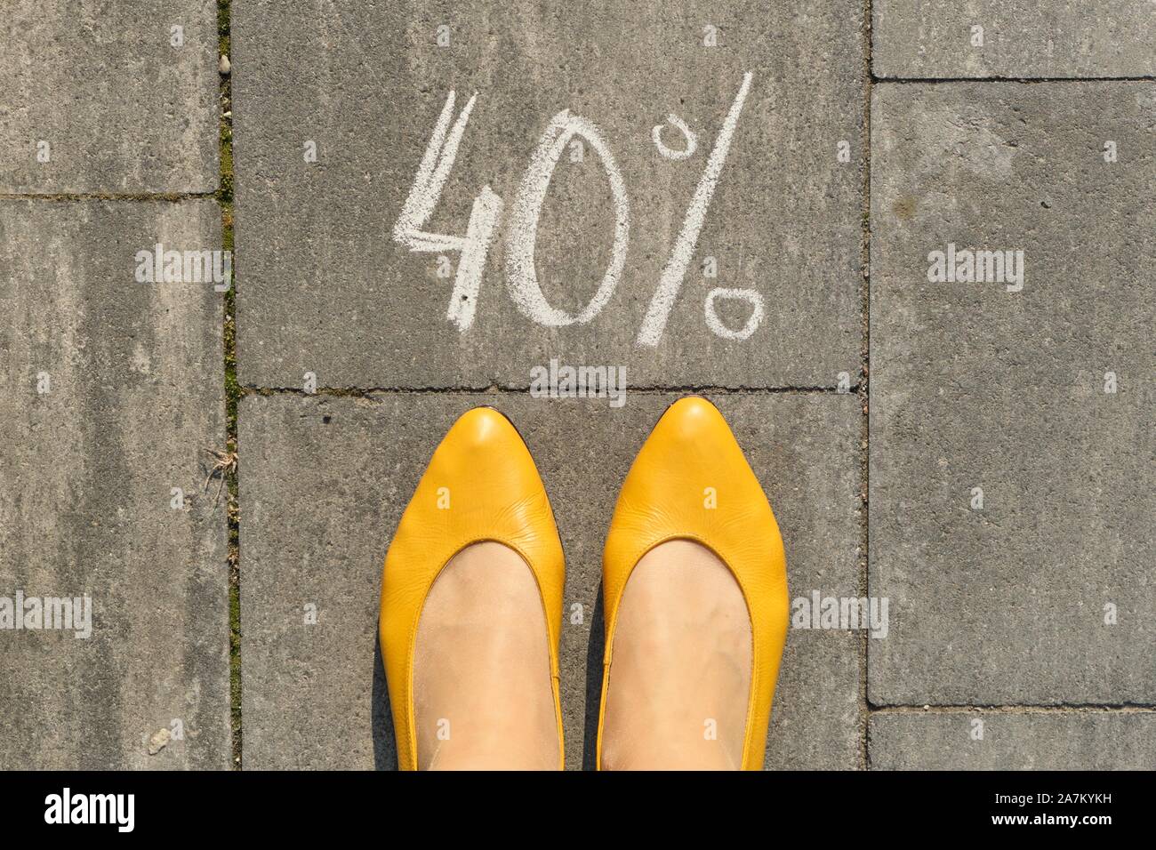 Text 40 percent written on gray pavement with woman legs, view from ...