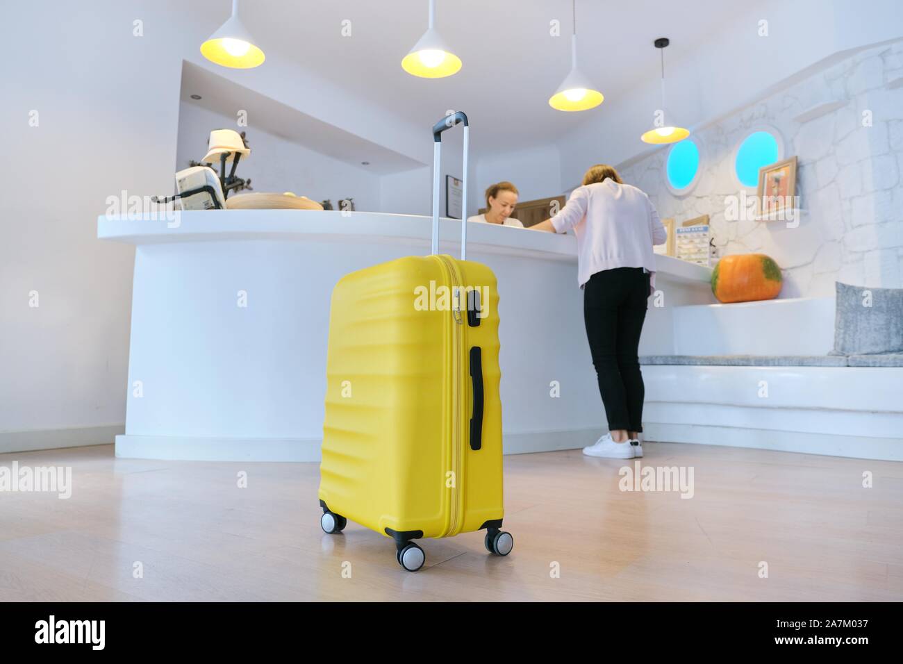 Yellow suitcase near reception desk in hotel lobby Stock Photo - Alamy