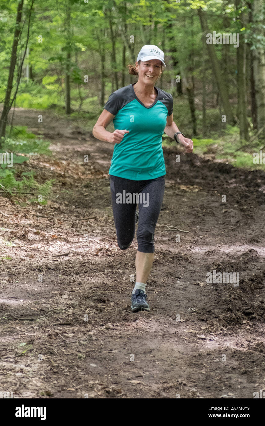 People running in a race along a wooded trail Stock Photo - Alamy