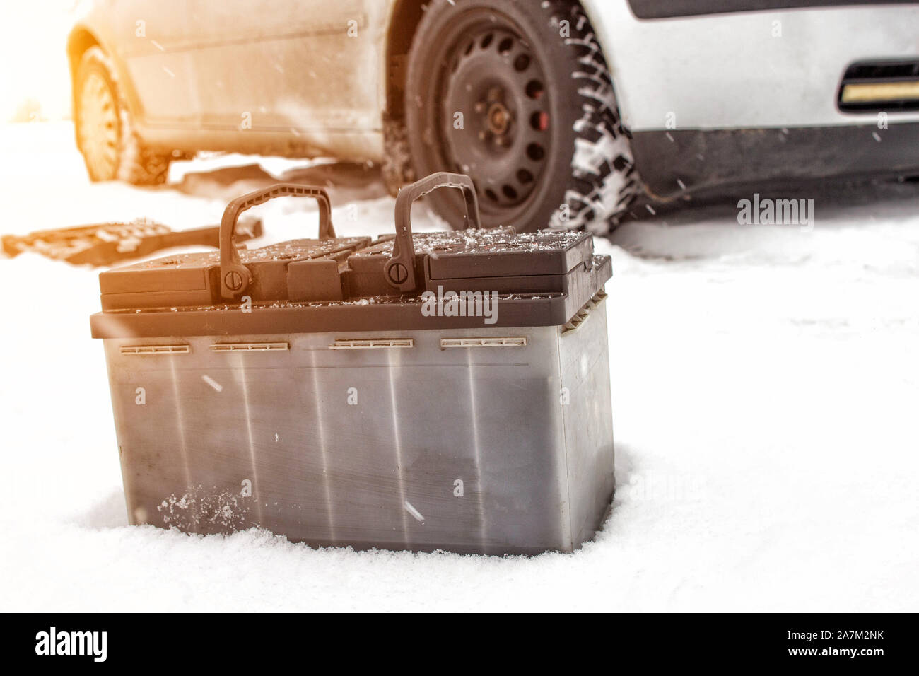 Car battery against the background of a car in winter. Winter battery ...
