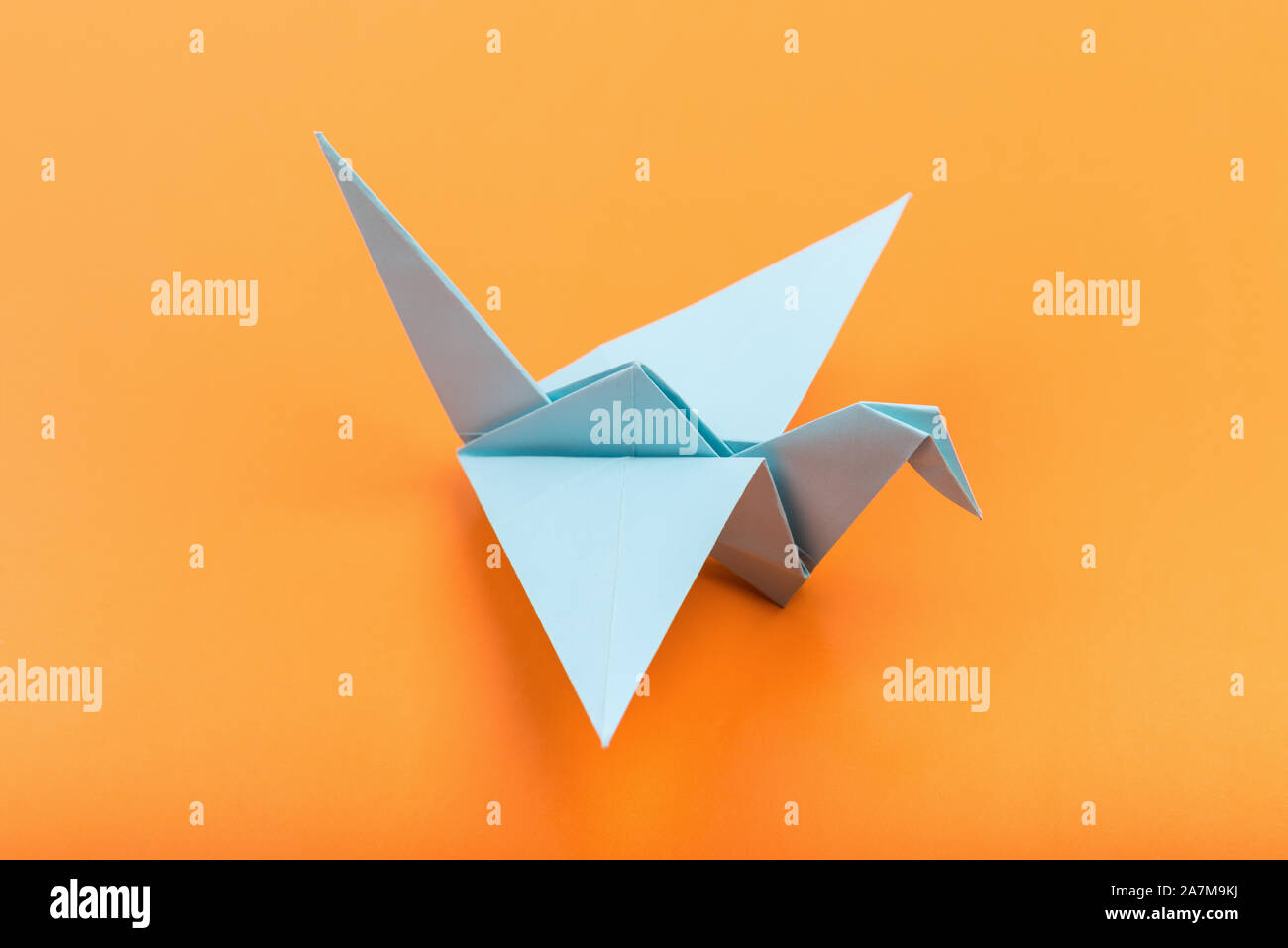 Origami bird on dark yellow background. Japanese folded paper swan ...