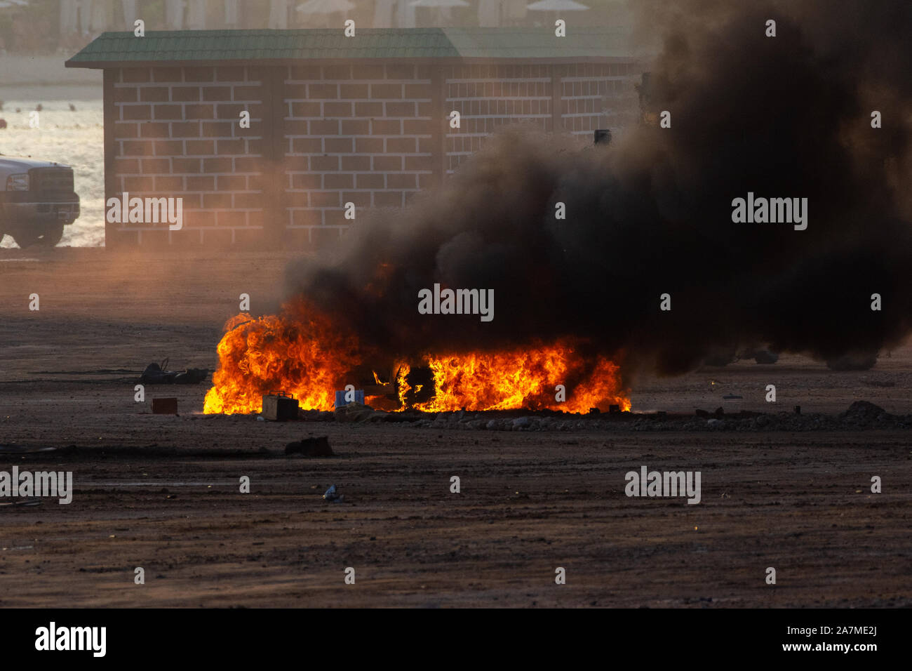 Military strike on a car sets it on fire after a riot in war. Smoke and ...