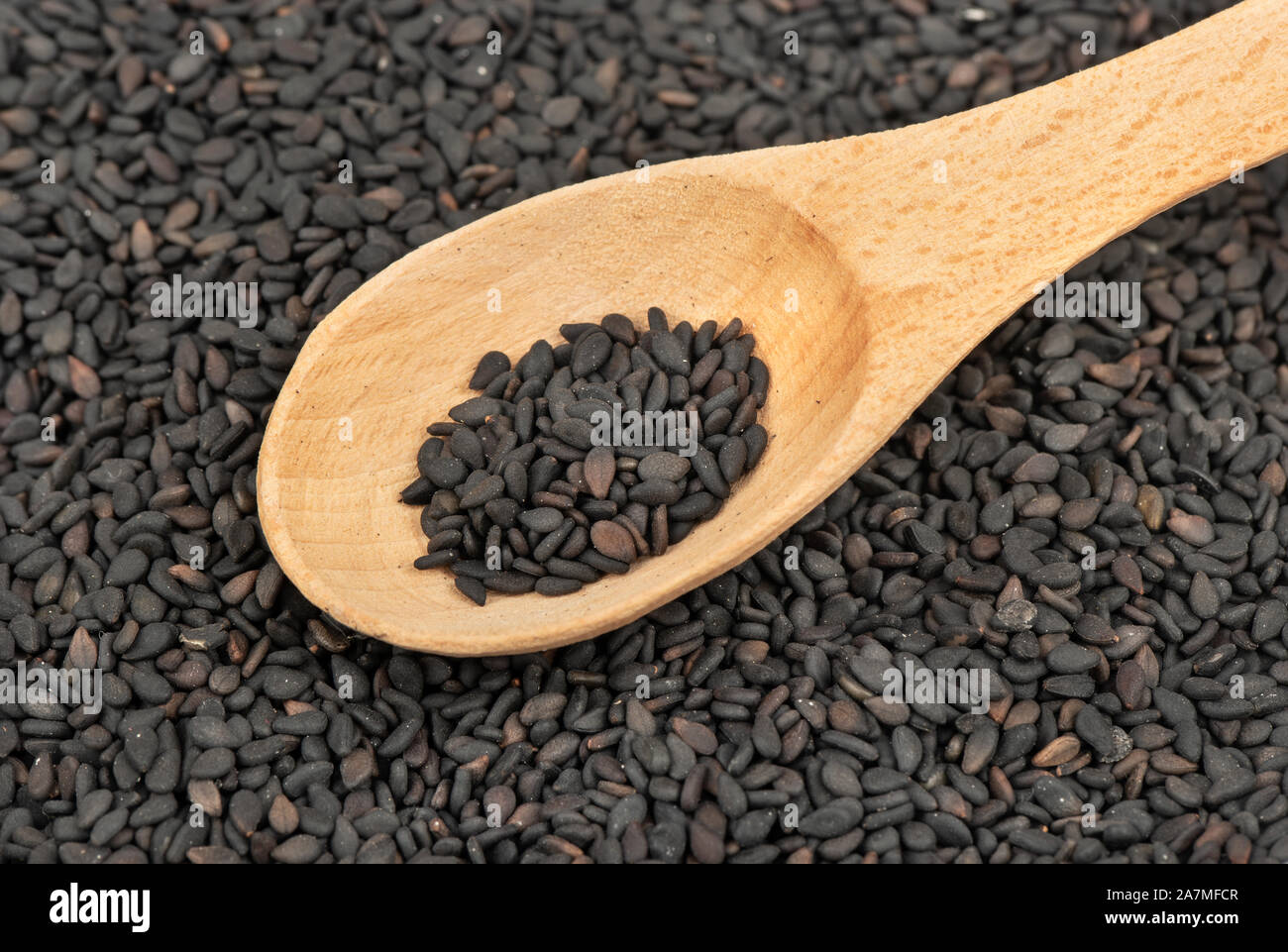 Pile of scattered black sesame seeds with a wooden spoon close up Stock ...