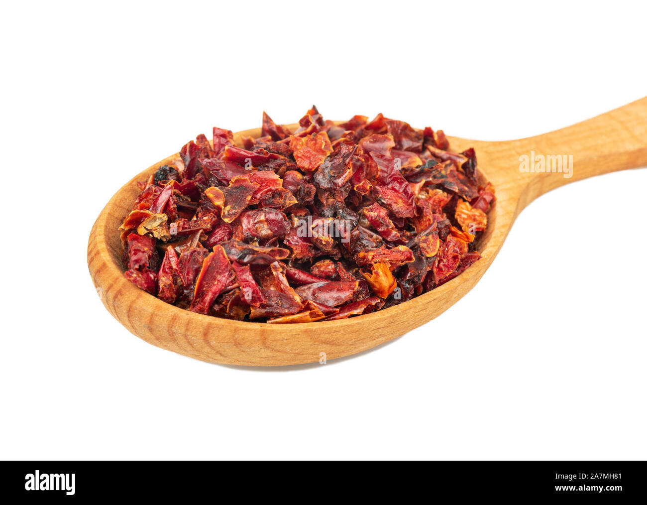 Pieces of dry red pepper in a large spoon closeup isolated on white ...