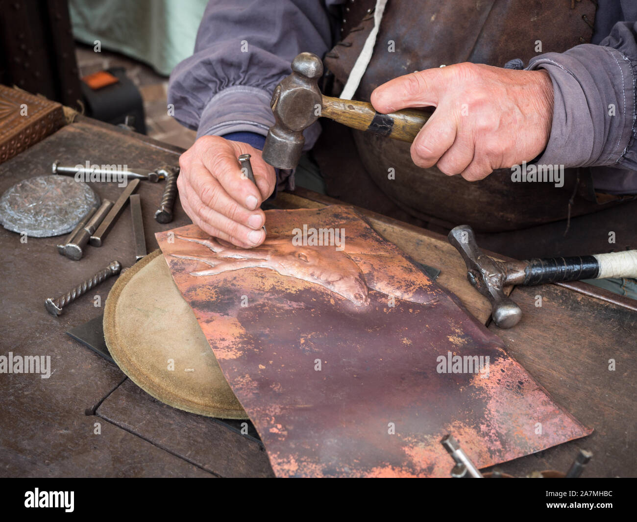 Craftsman cuts a copper plate with a hammer and chisel Stock Photo - Alamy