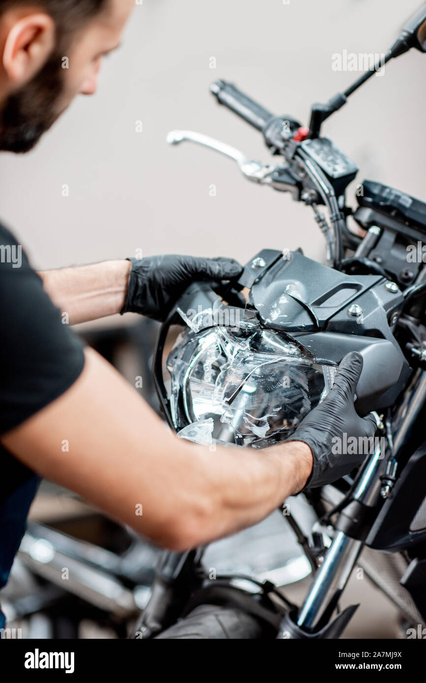Worker removing broken headlight after the accident, repairing ...