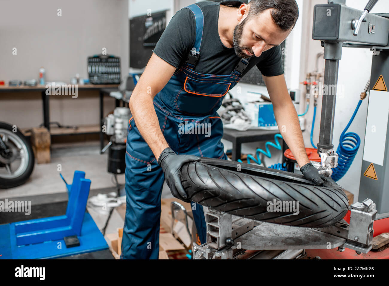 Service worker changing motorcycle tire on a special equipment for tire ...