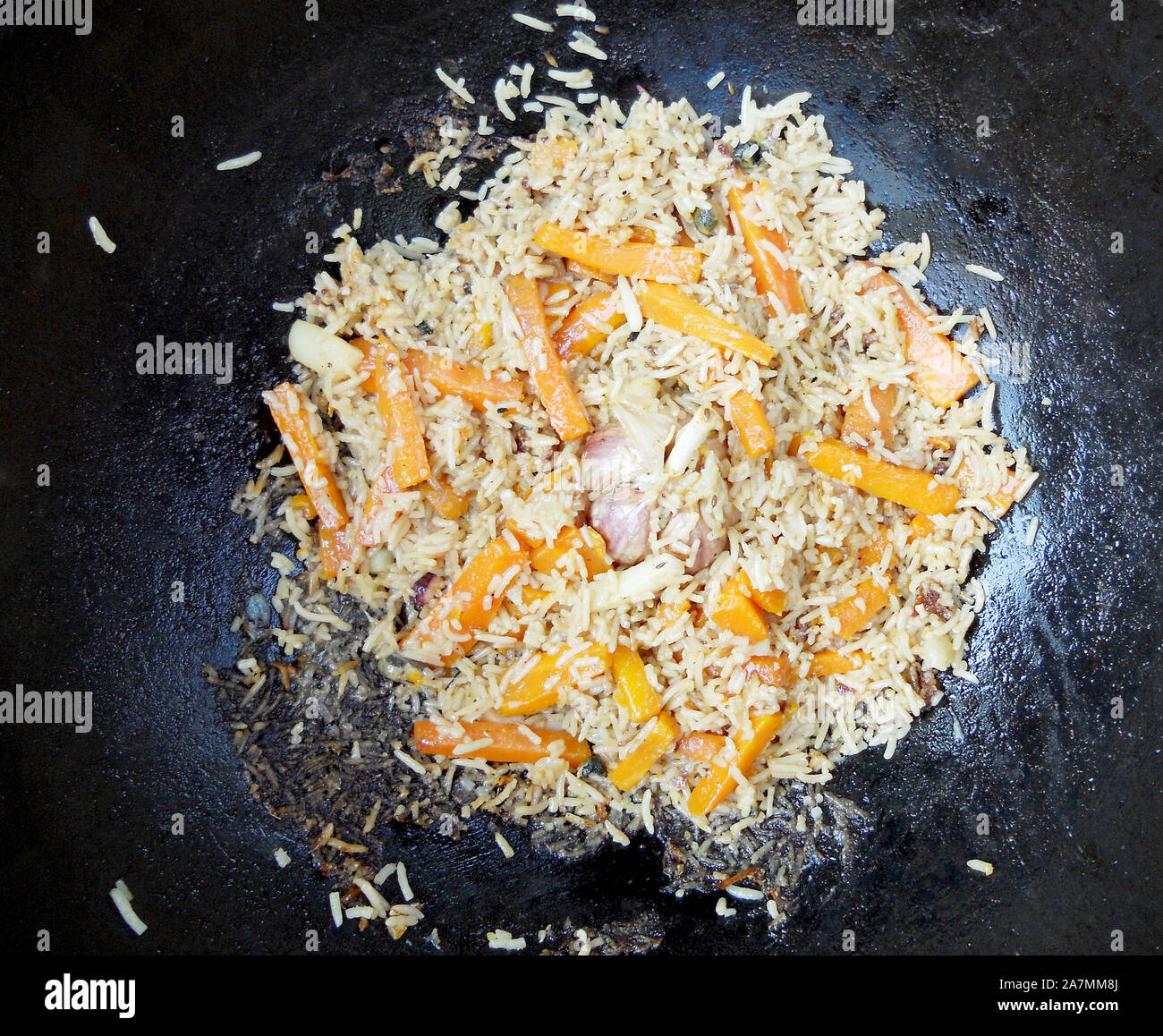 Cast iron bowl pilaf, wide black plate is filled with various homemade ...