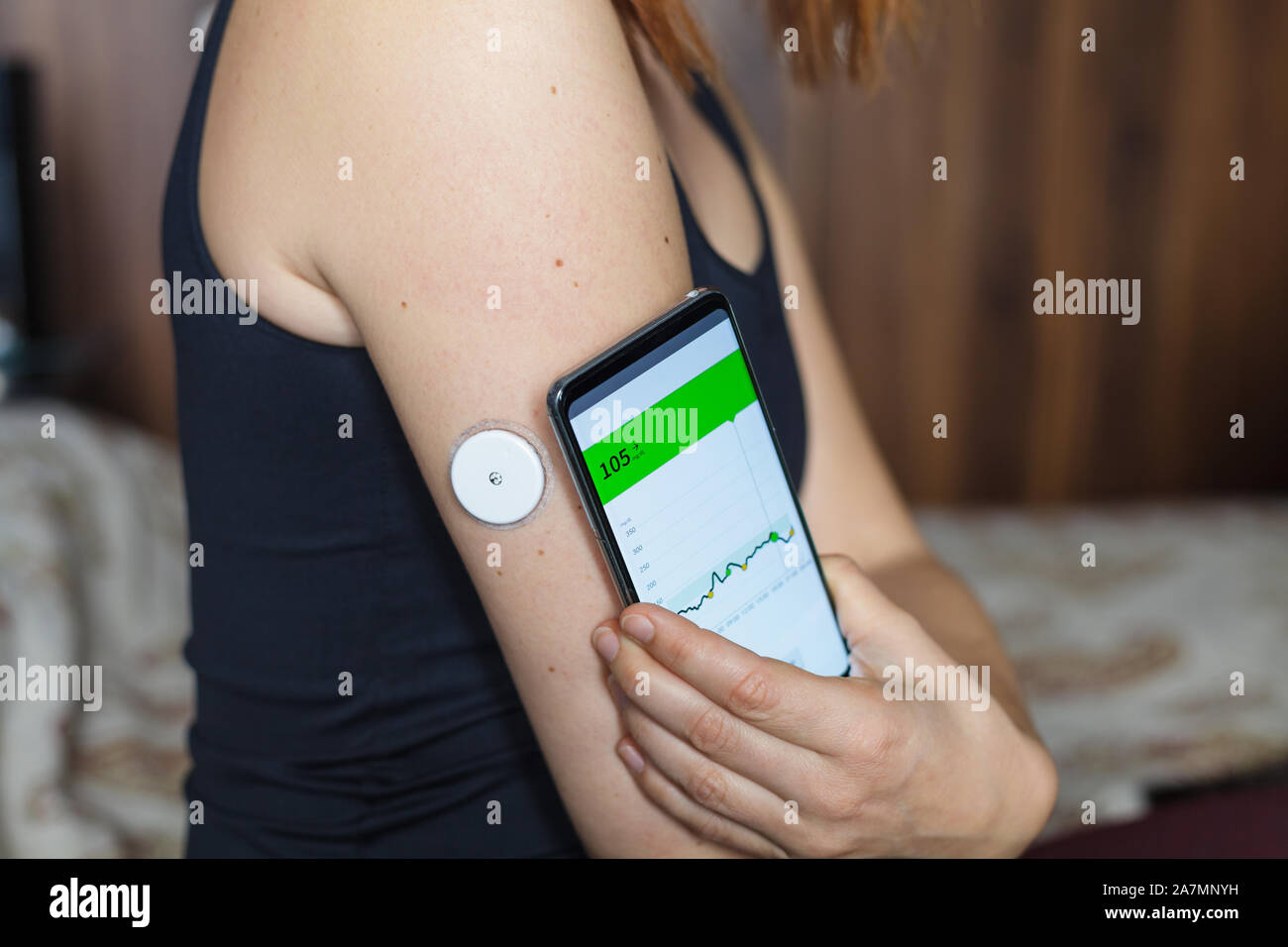 Woman checking glucose level with a modern technology remote sensor and ...