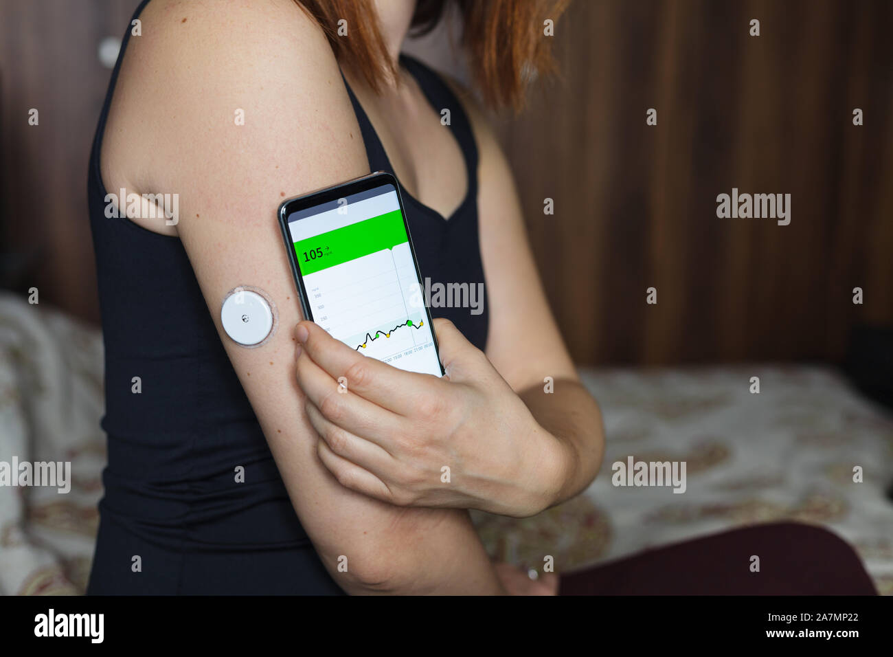 Woman checking glucose level with a modern technology remote sensor and ...