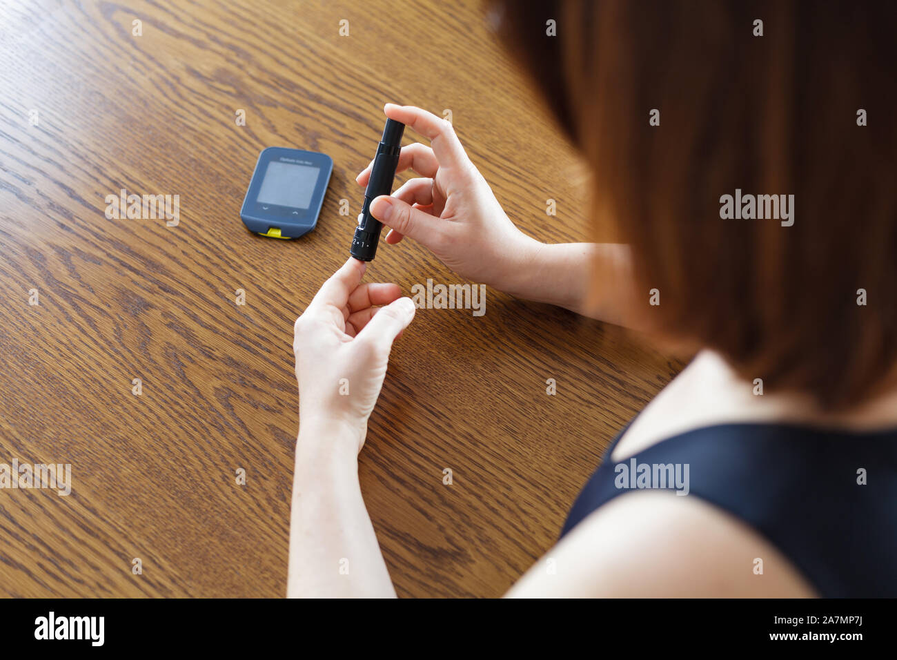 Woman using lancet to take blood sample to check glucose level with ...