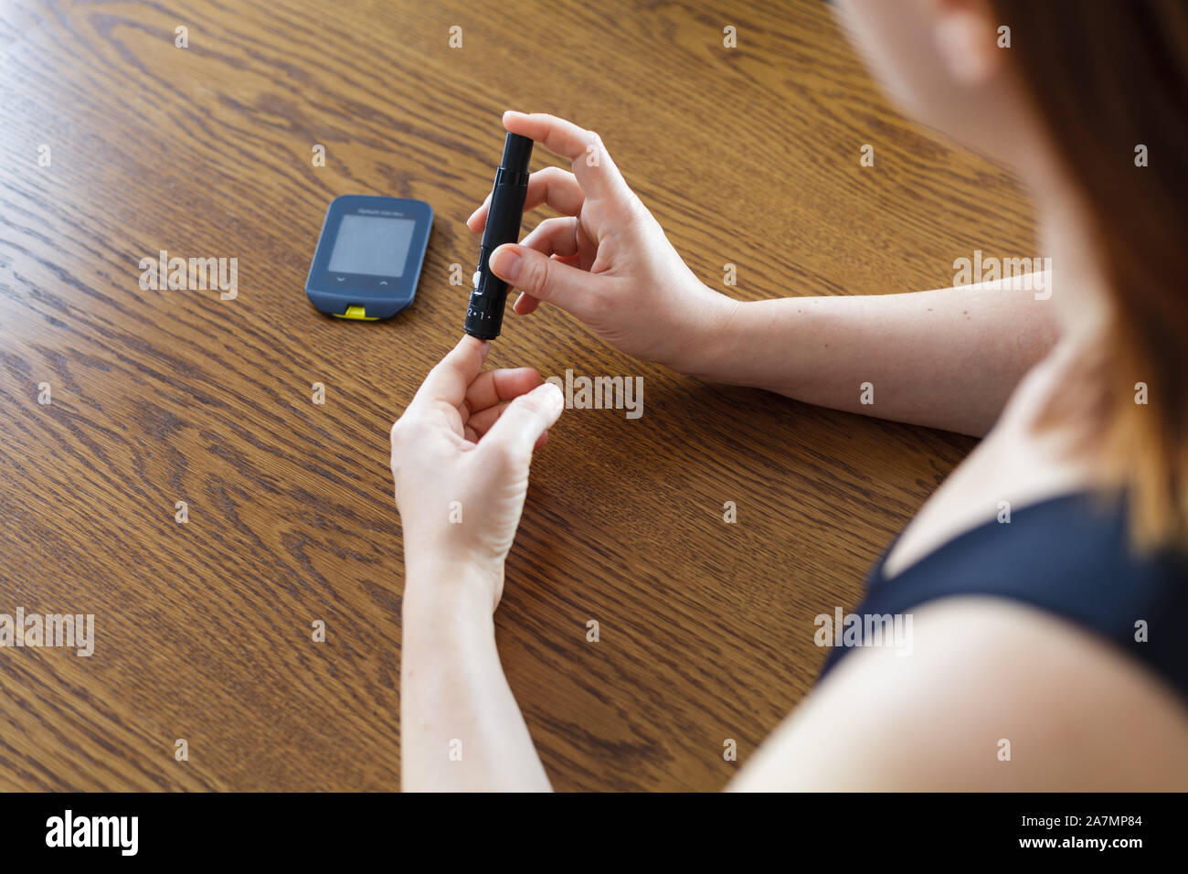 Woman using lancet to take blood sample to check glucose level with ...