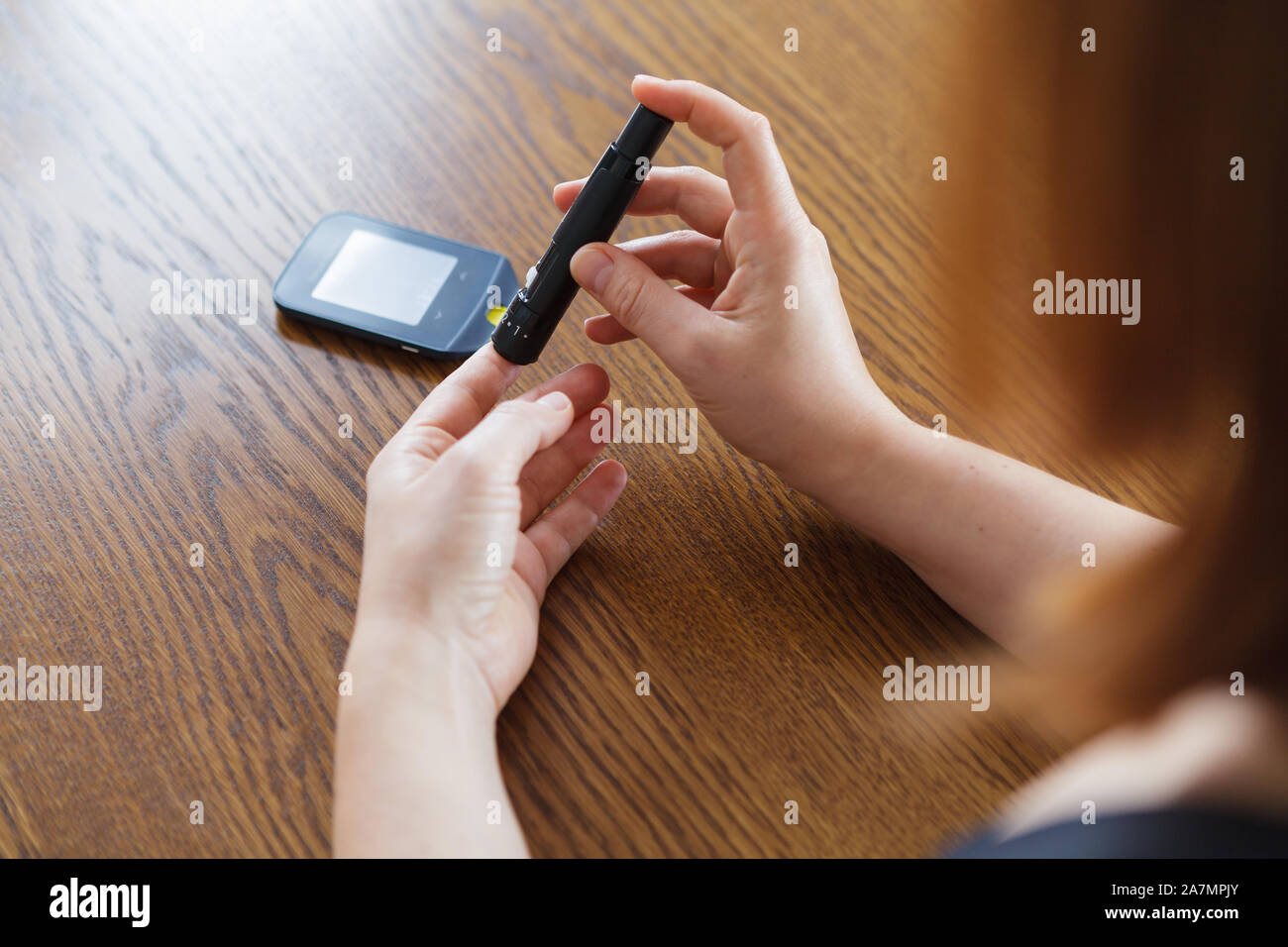 Woman using lancet to take blood sample to check glucose level with ...