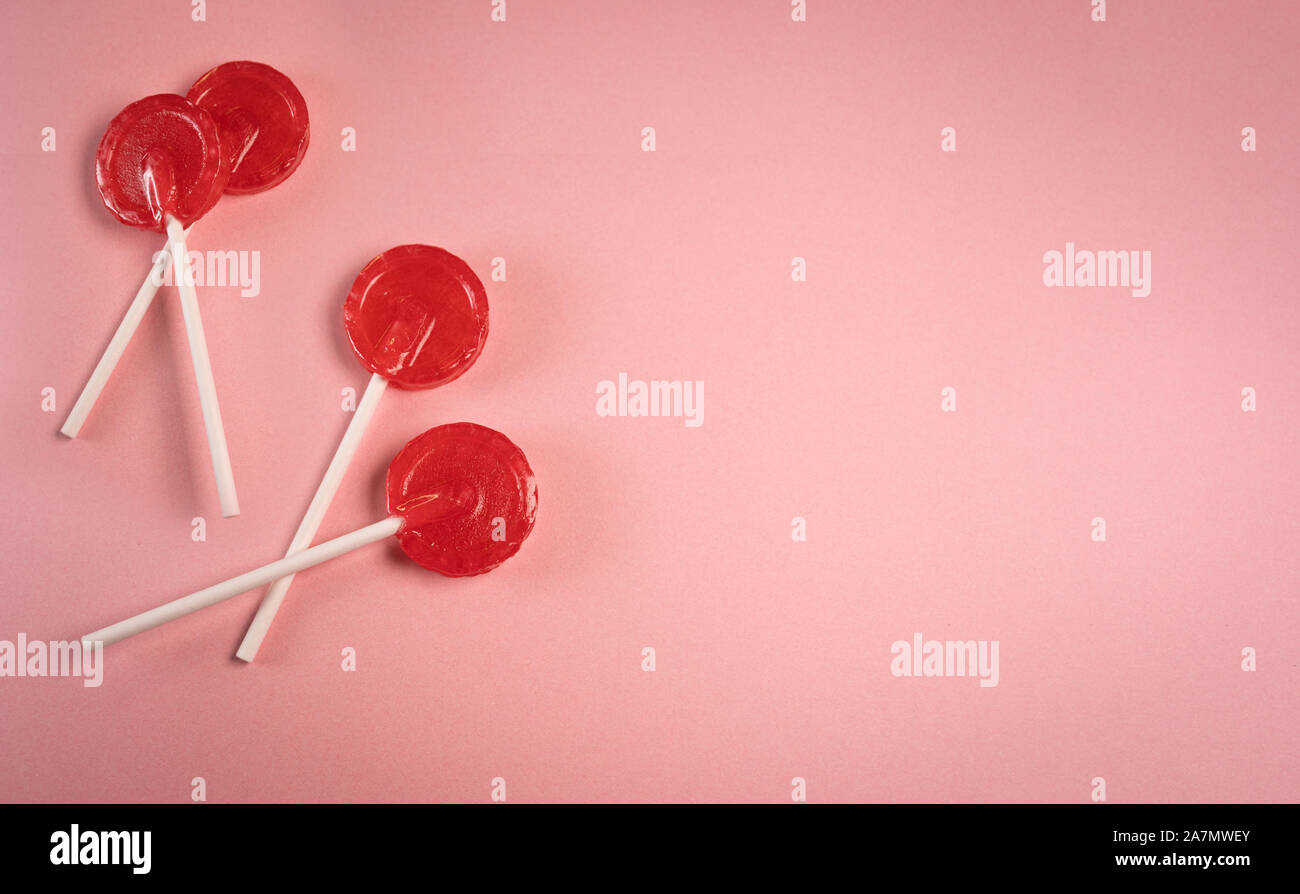 Round shaped red sweet tasty lollipops on pink pastel background. Copy ...
