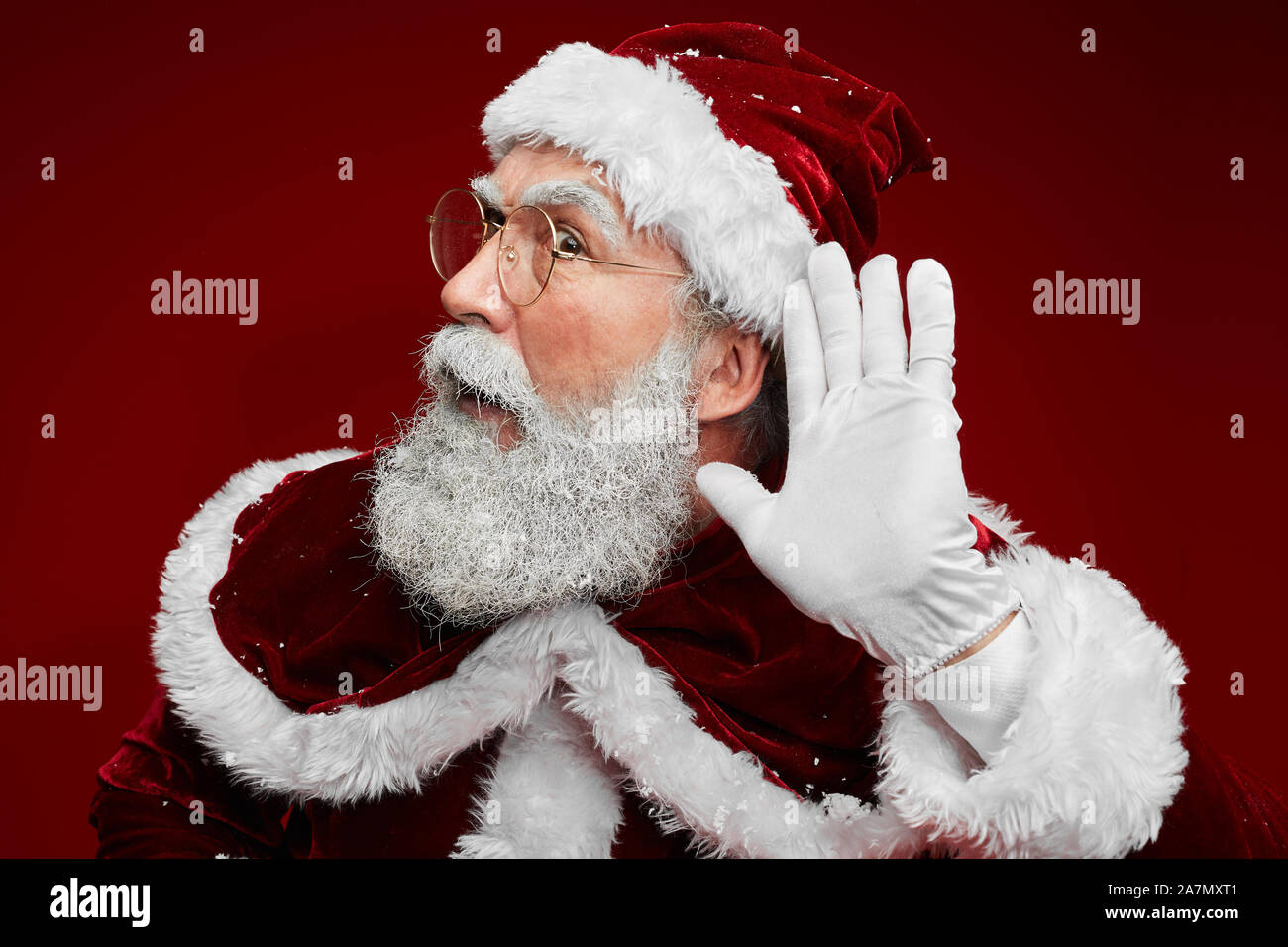 Portrait of classic Santa Claus putting hand to ear trying to hear ...