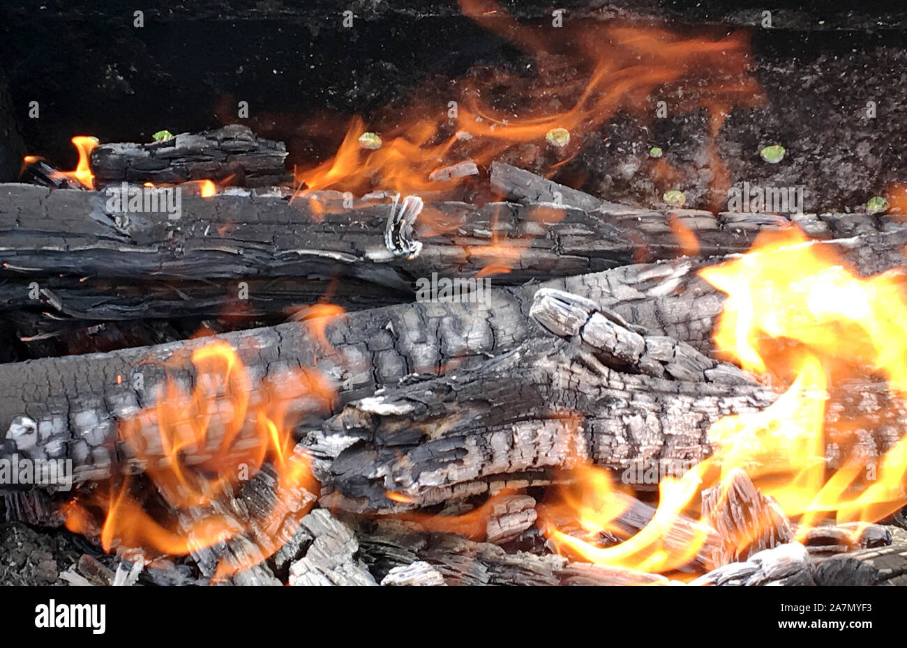 Beautiful red flame from slice wood, dark grey black coals inside metal ...