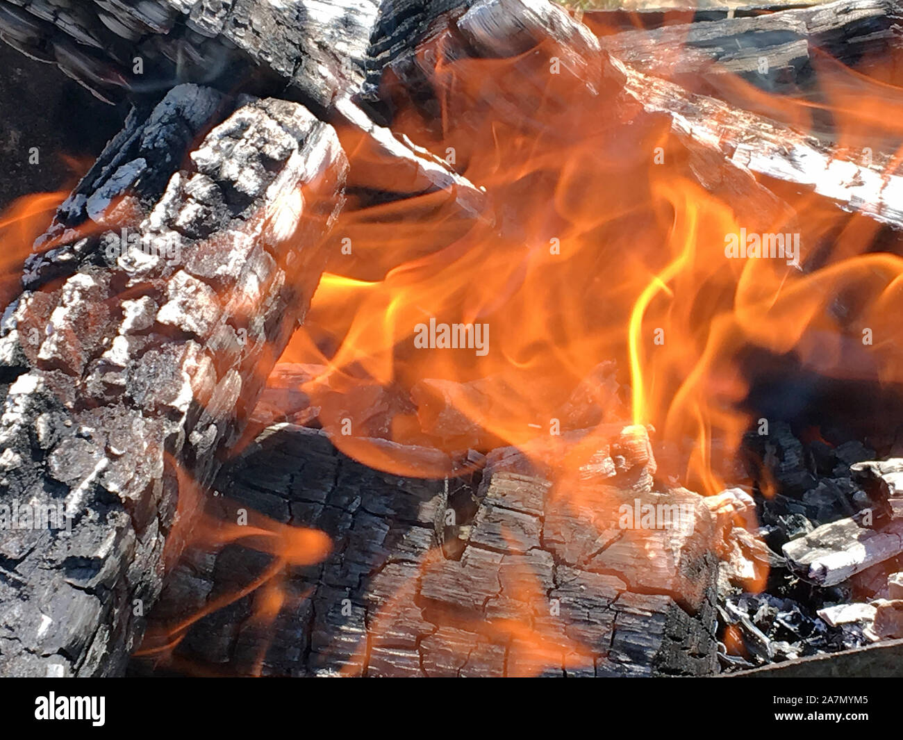 Beautiful red flame from slice wood, dark grey black coals inside metal ...