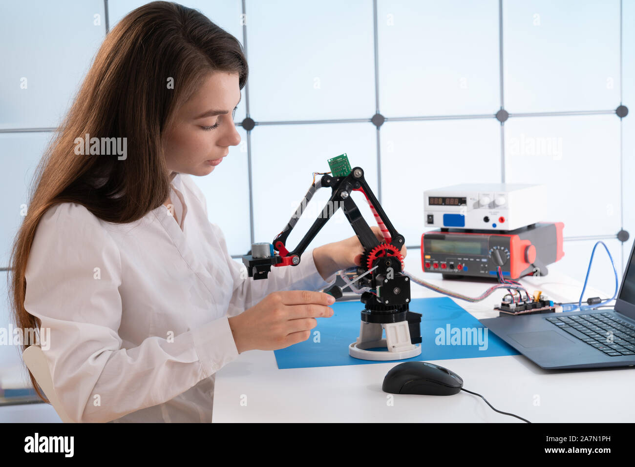 A young woman writes an algorithm for the robot arm. Science Research ...