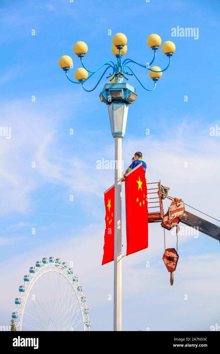 Workers hang national flags in streets to celebrate the 70th National ...