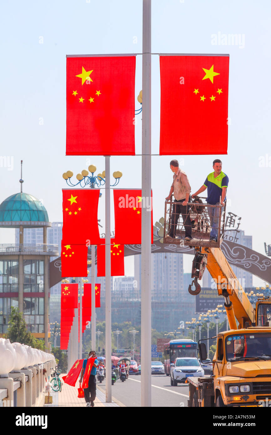 Workers hang national flags in streets to celebrate the 70th National ...