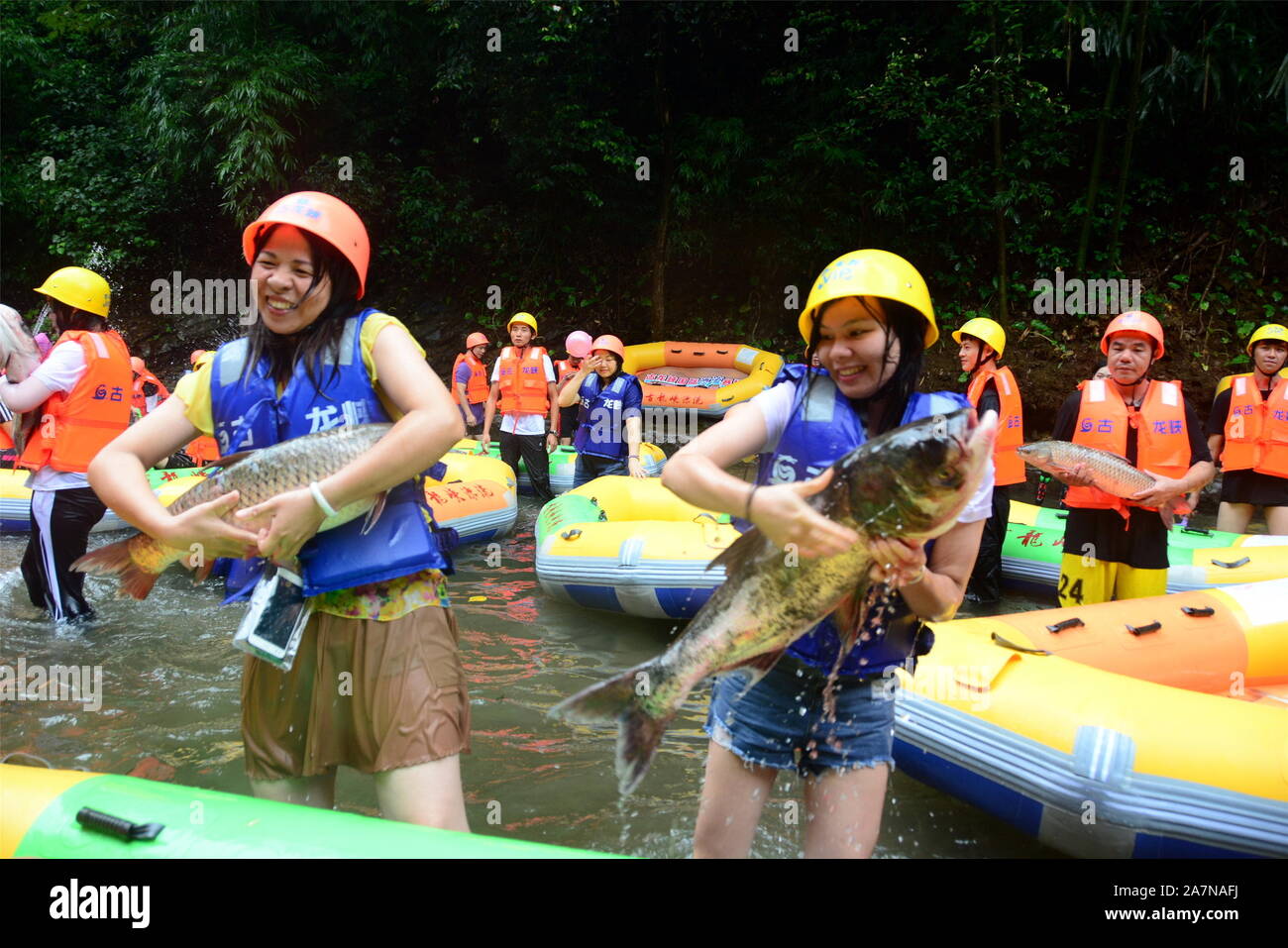 A crowd of tourists sitting on inflatable rafts jam a stream and catch ...