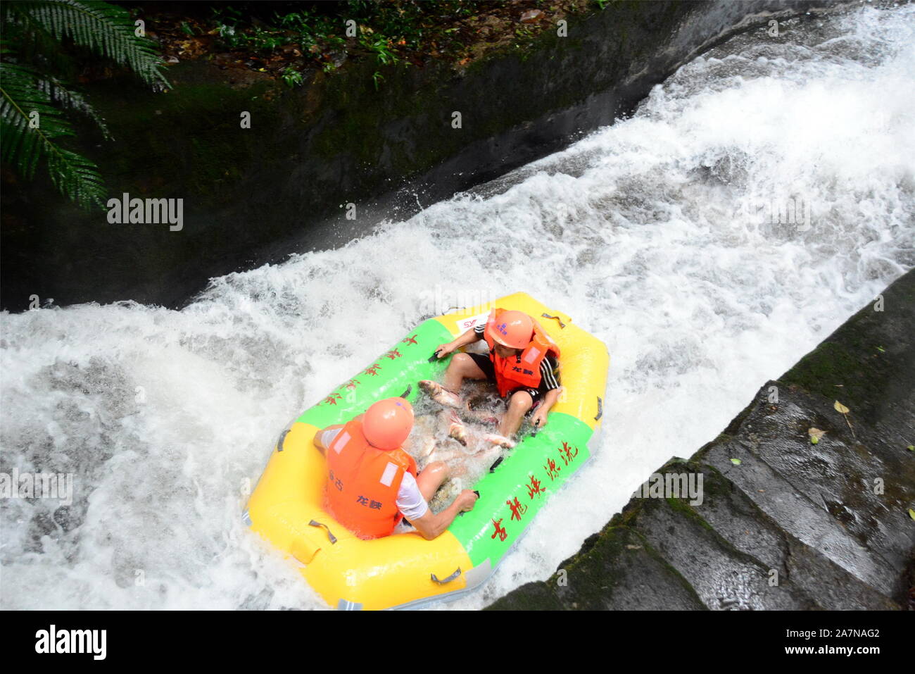 A crowd of tourists sitting on inflatable rafts jam a stream and catch ...