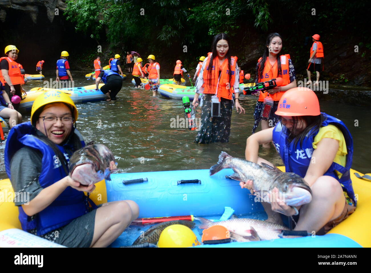 A crowd of tourists sitting on inflatable rafts jam a stream and catch ...