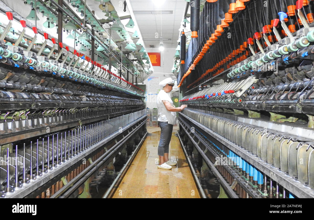 A female Chinese worker handles production of yarn at a textile factory in Lianyungang city ...