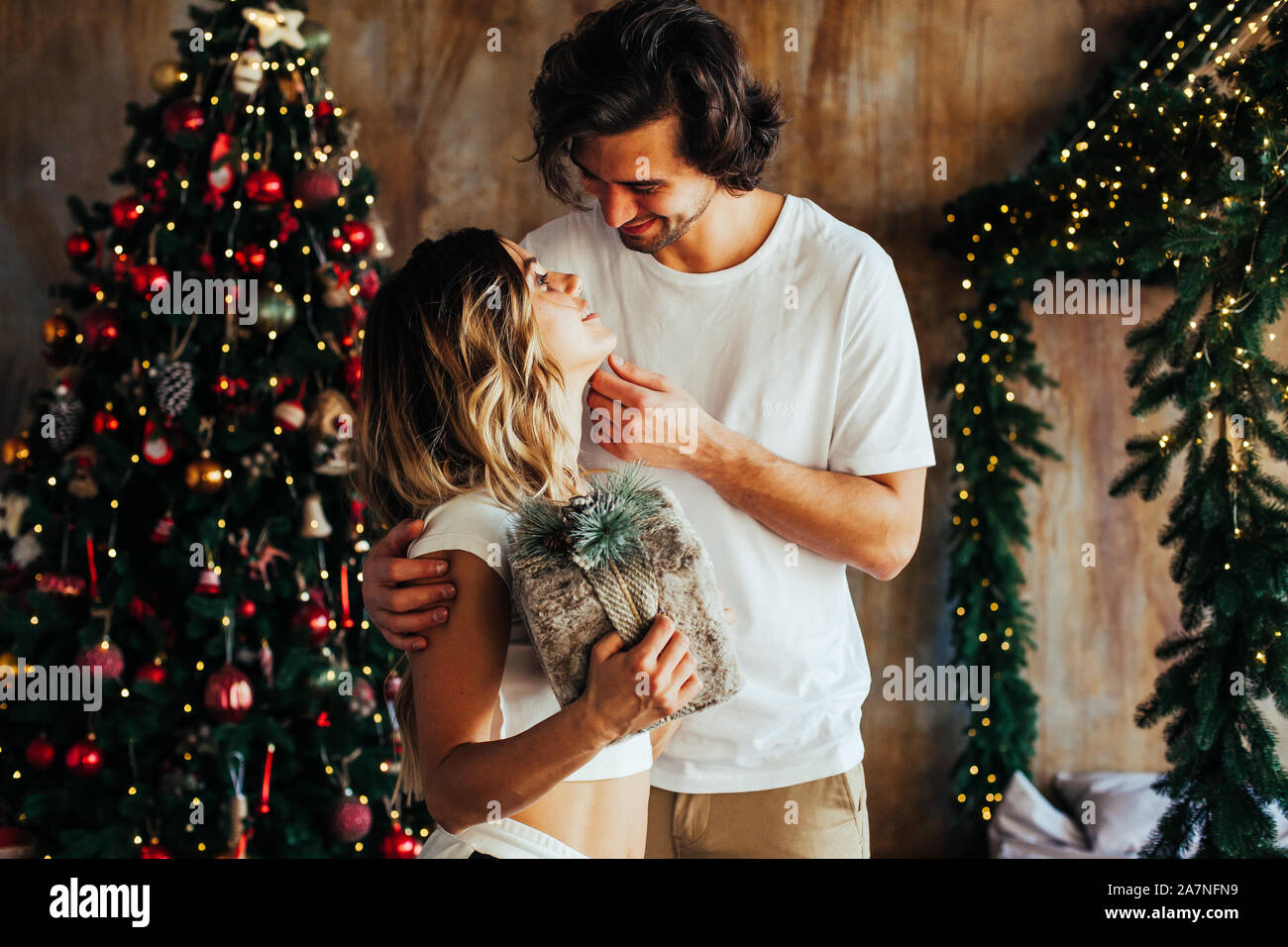 Young man hugging a young woman holding a wrapped gift box Stock Photo ...