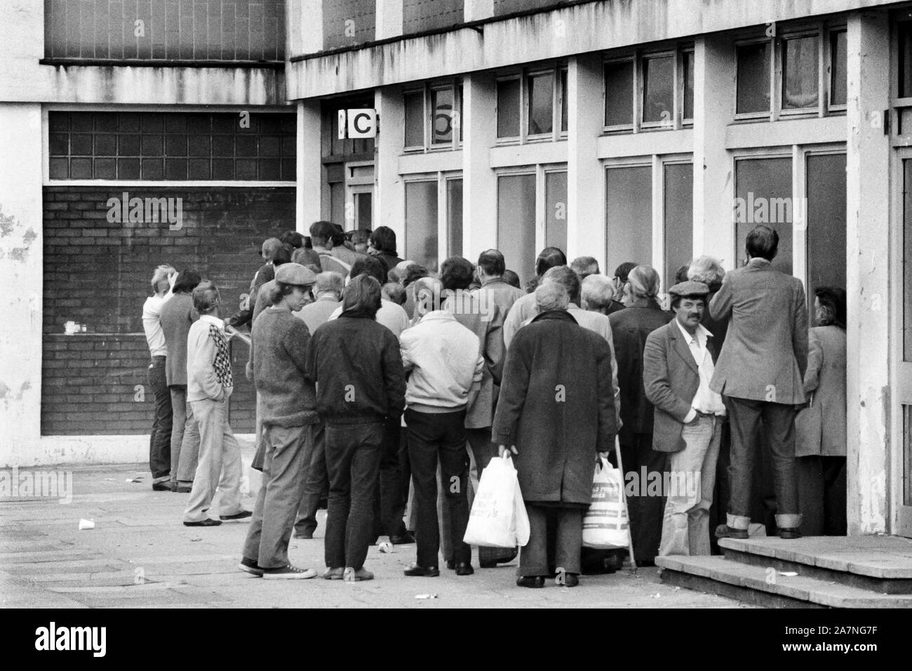 Unemployed men queue at a South London, UK, DHSS office in the 1980's ...