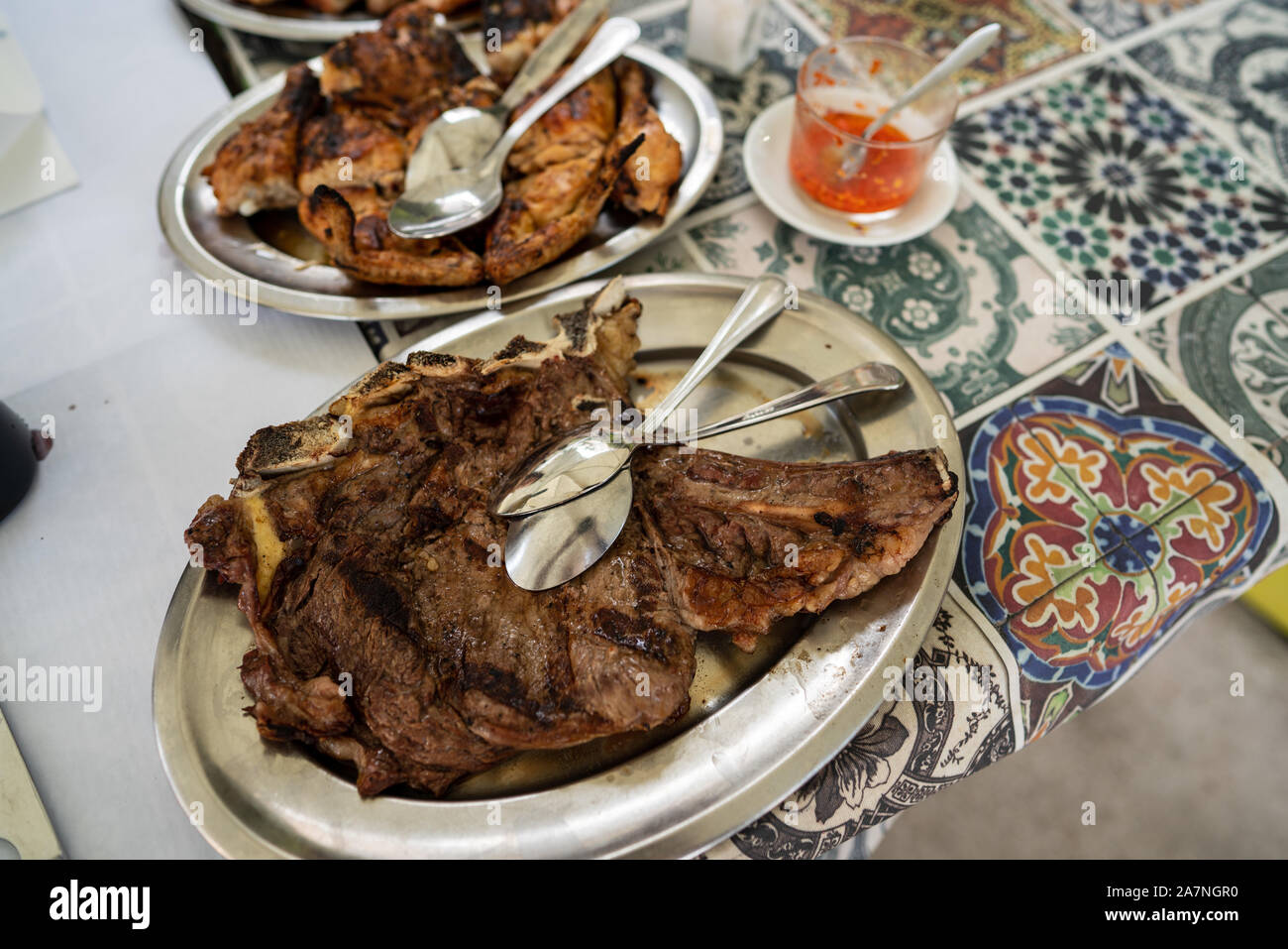 Beef steak and chicken platters on table with color table cloth on ...