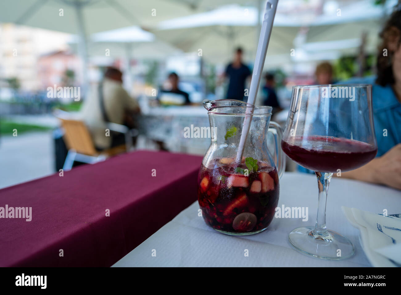 Pitcher and glass of fruity red sangria at an outdoor restaurant with ...