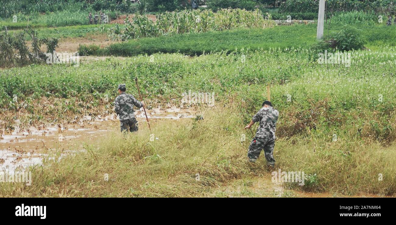 Chinese rescuers walk on a road covered with mud and stones after heavy ...