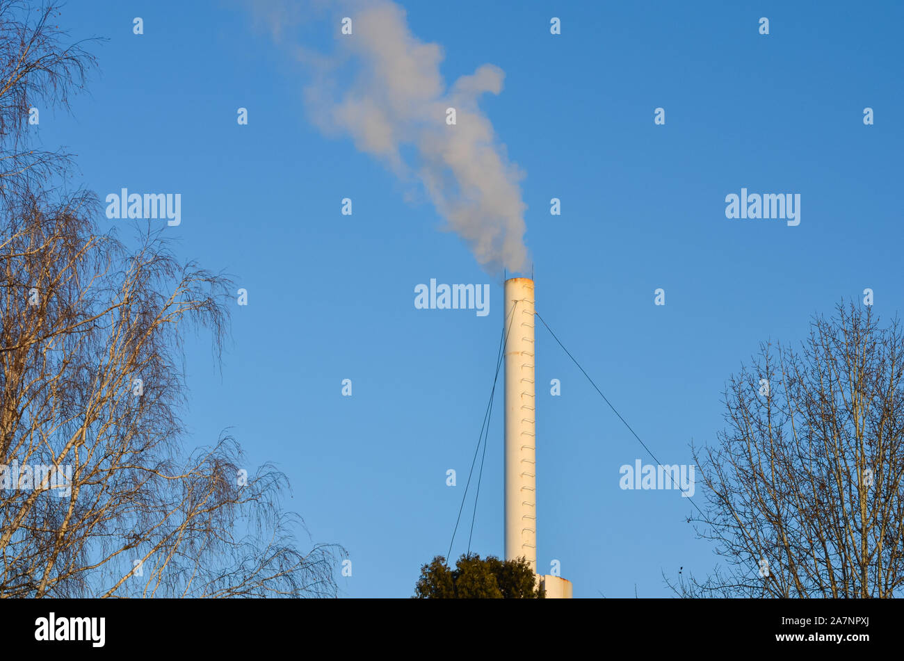 Industrial smoking pipe emitting smoke from factory against blue sky ...