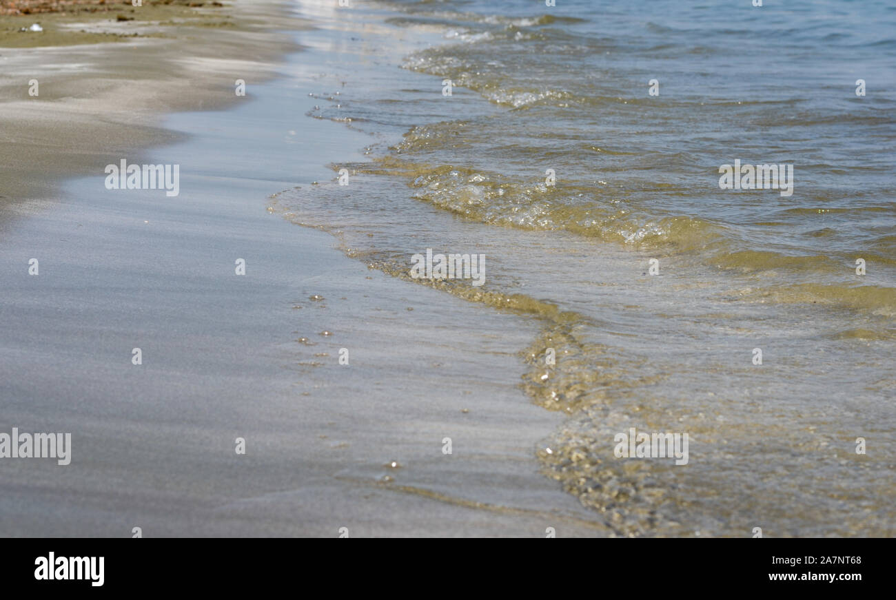 Close-up of sea shore edge and sand with clear water waves Stock Photo ...