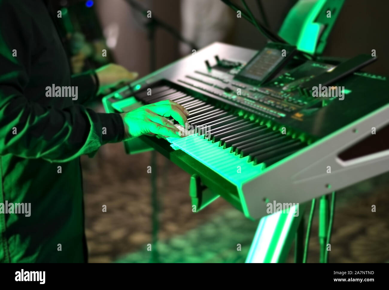 Close-up hand of a man singing at an electronic synthesizer at a party ...
