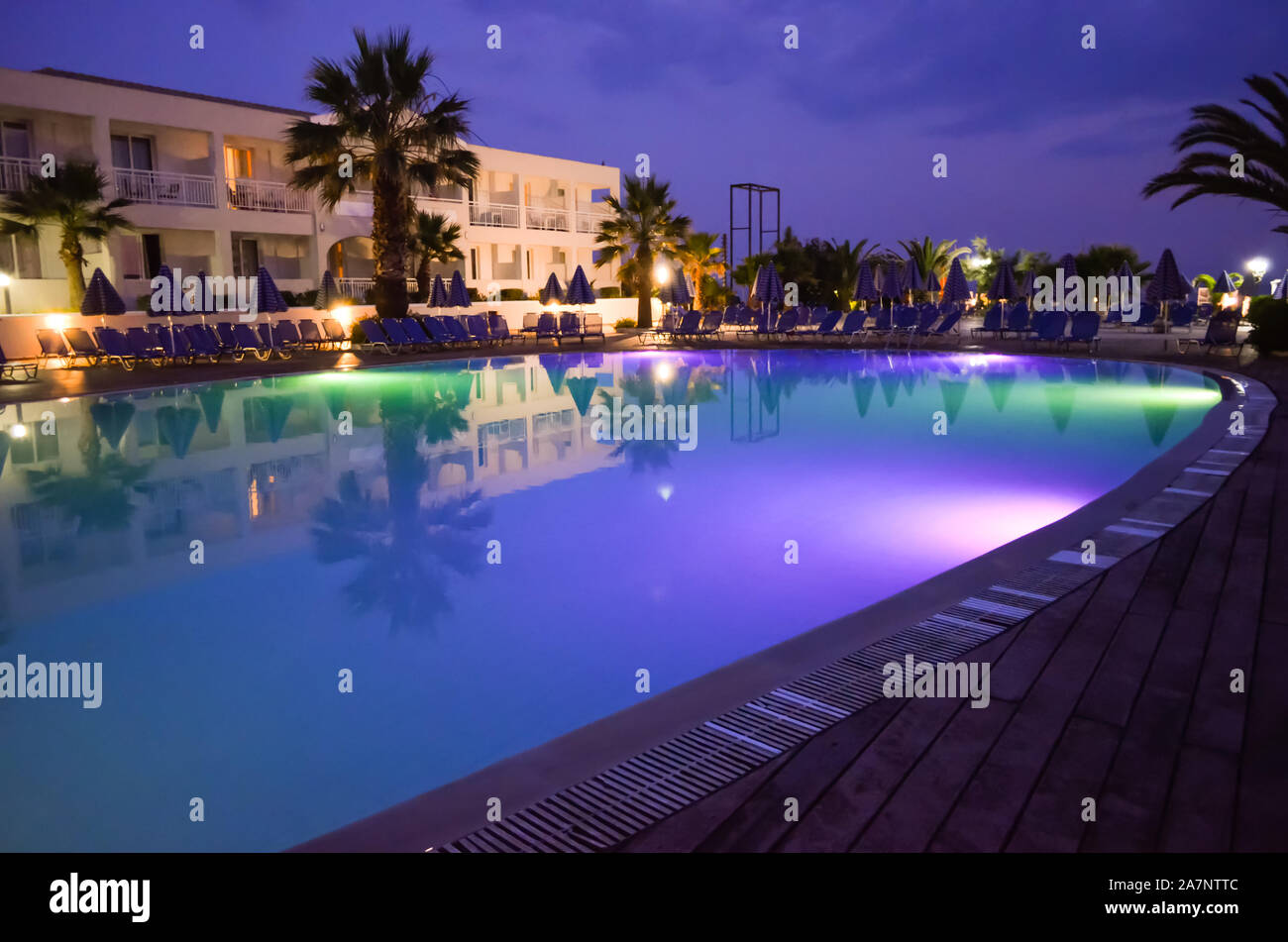 Multicolored illuminated swimming pool at hotel resort during night ...