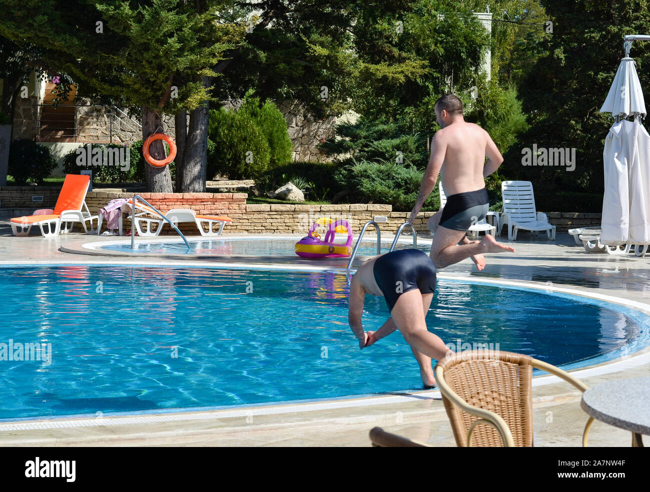 Two young men jumping in swimming pool Stock Photo - Alamy