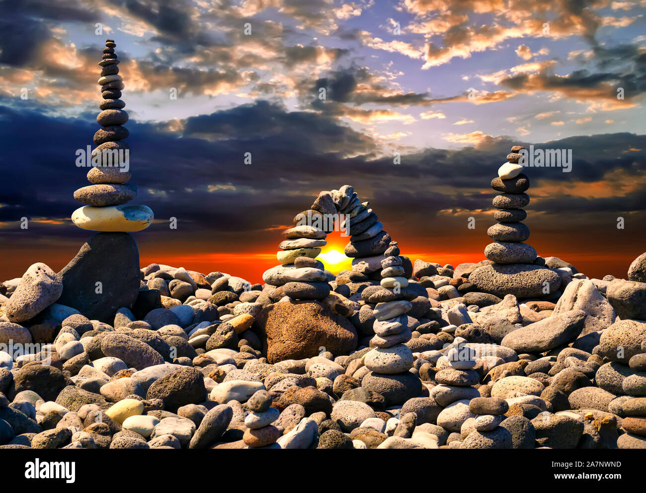 Stacked stones on the beach at sunset. Sunlight between the stones ...