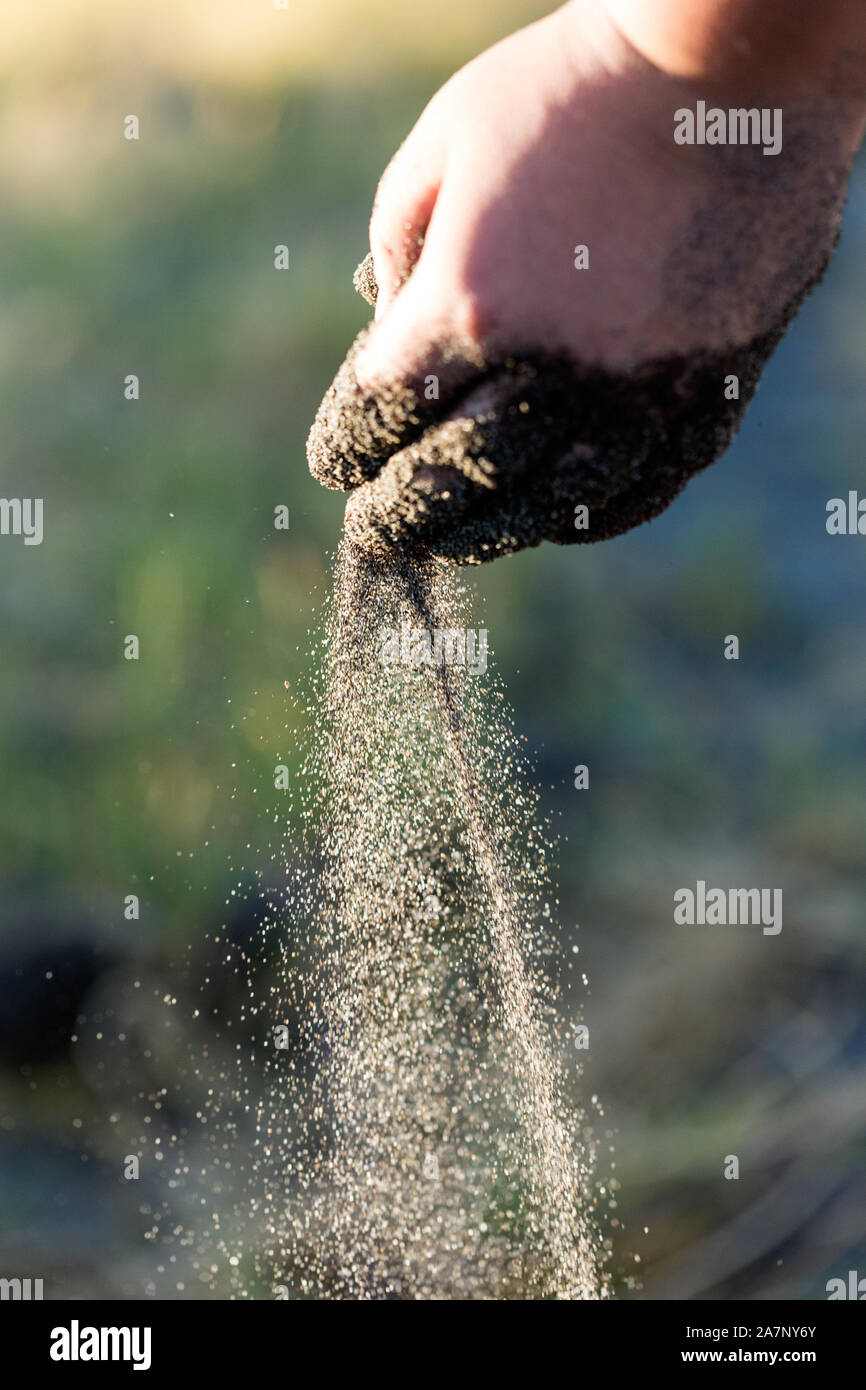 Sifting sands falling from a childs hand Stock Photo - Alamy