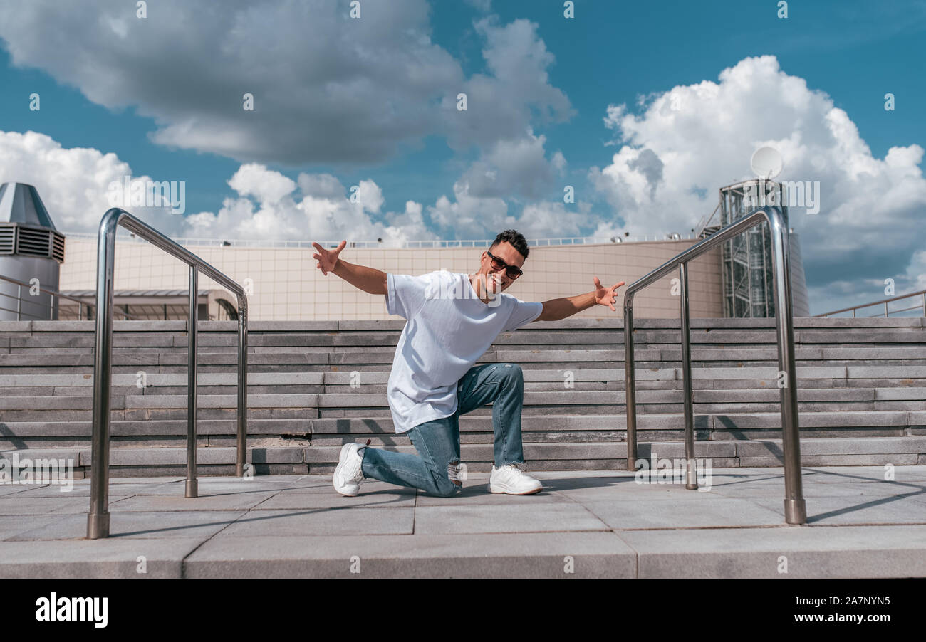 Happy male dancer dancing breakdance, in summer in city, steps cloud ...