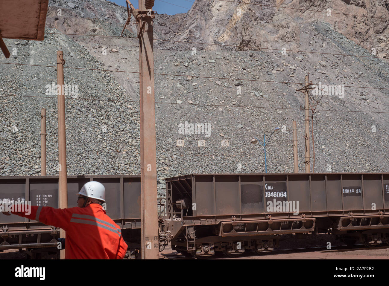 --FILE--A Chinese worker loads iron ore into a cargo train at a mine ...