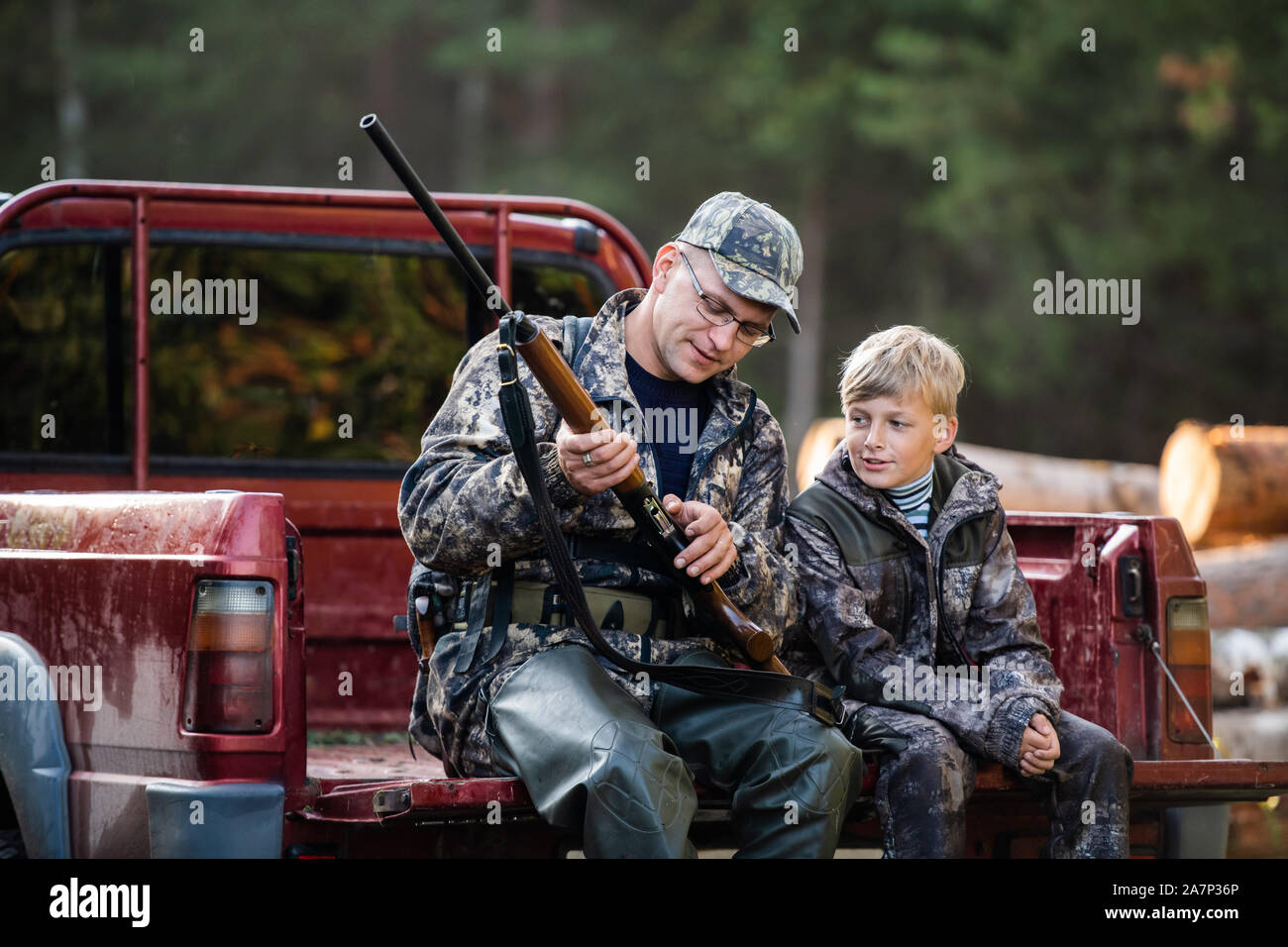 Father and son sitting in a pickup truck after hunting in forest. Dad ...