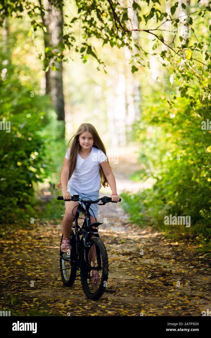 Cute little teenager girl riding bicycle in a sunny park Stock Photo ...