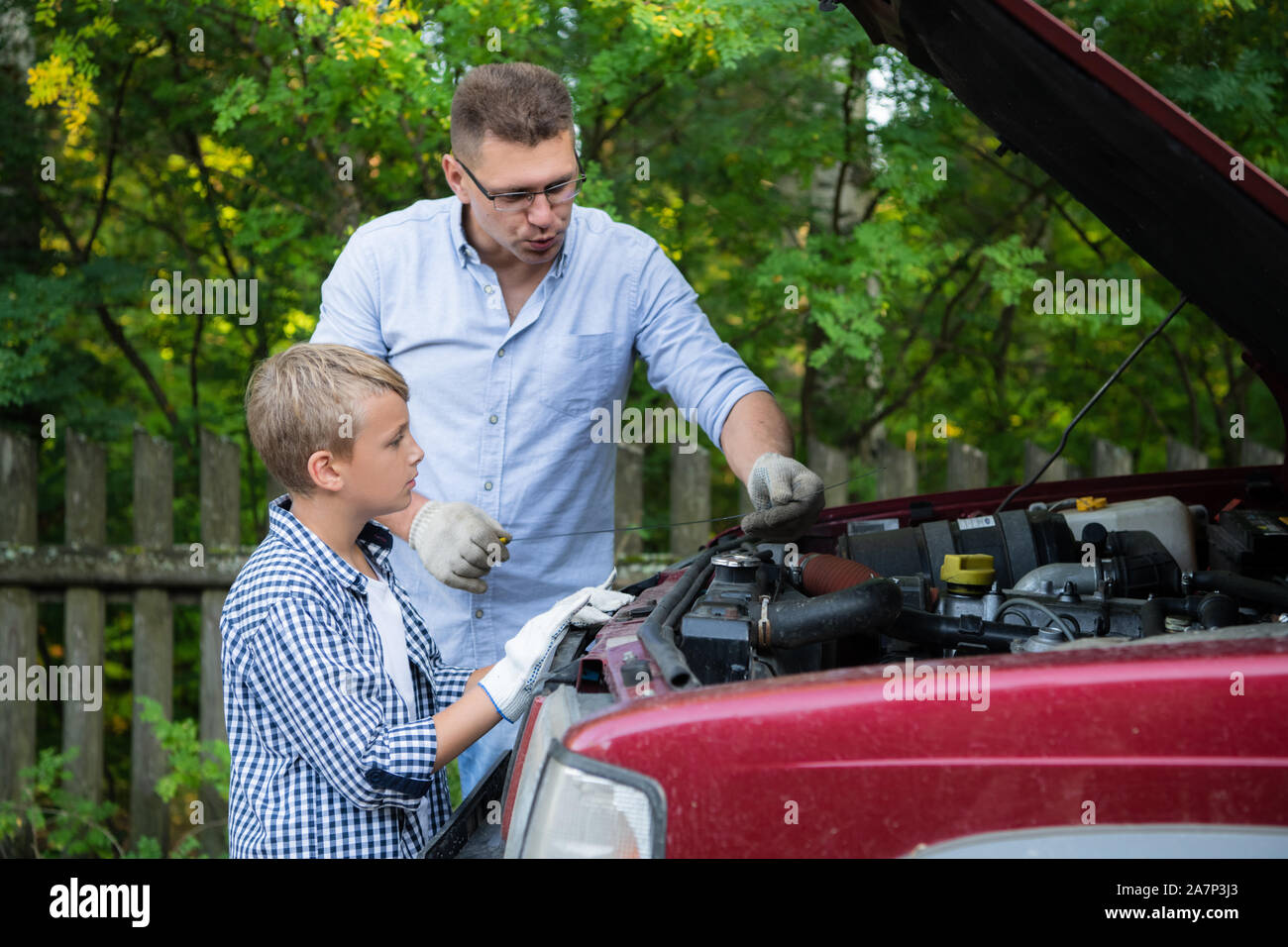 Father and son are repairing the car outdoors. Auto repair concept ...